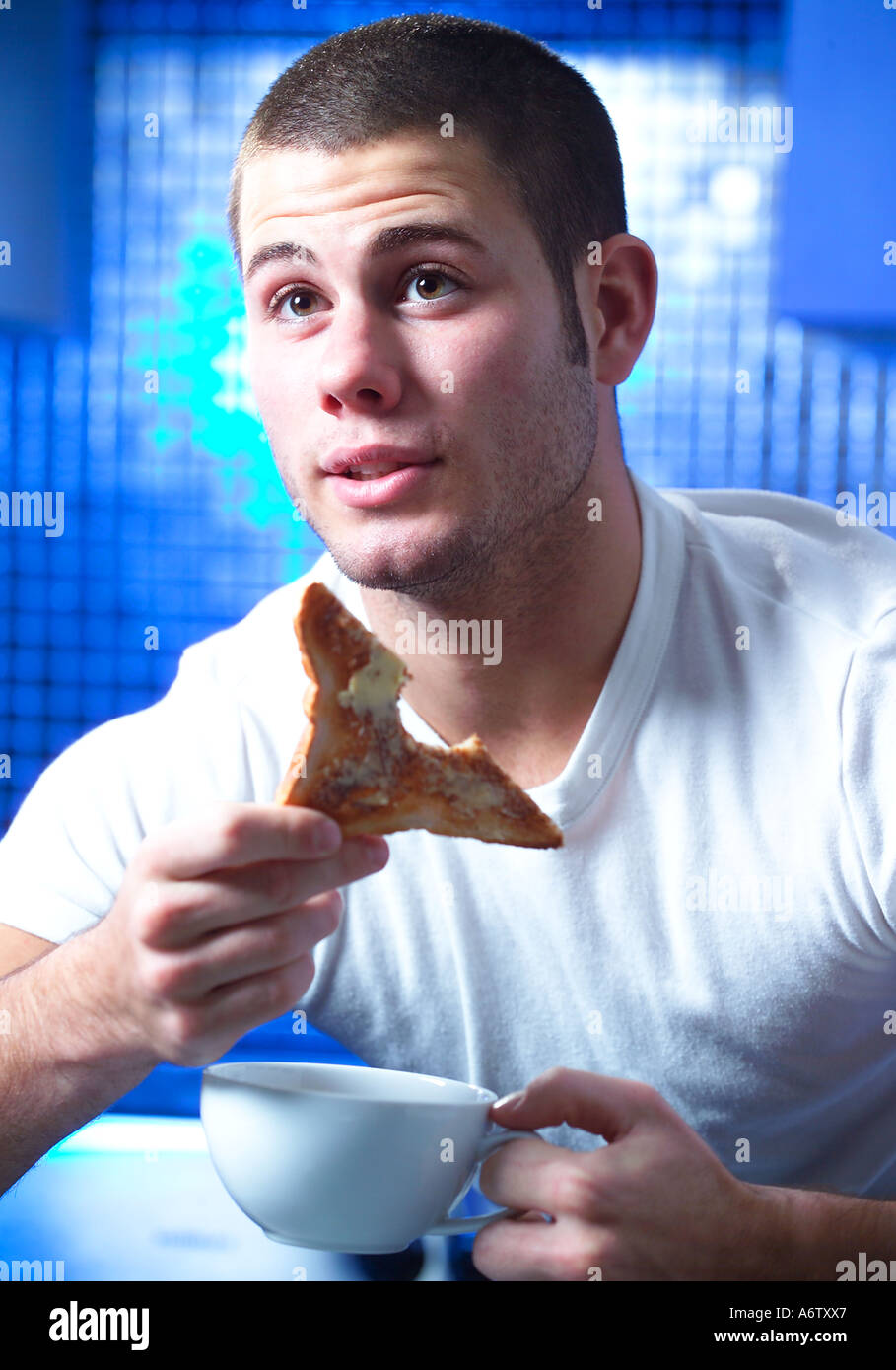 Young Man eating breakfast, coffee and toast Stock Photo - Alamy