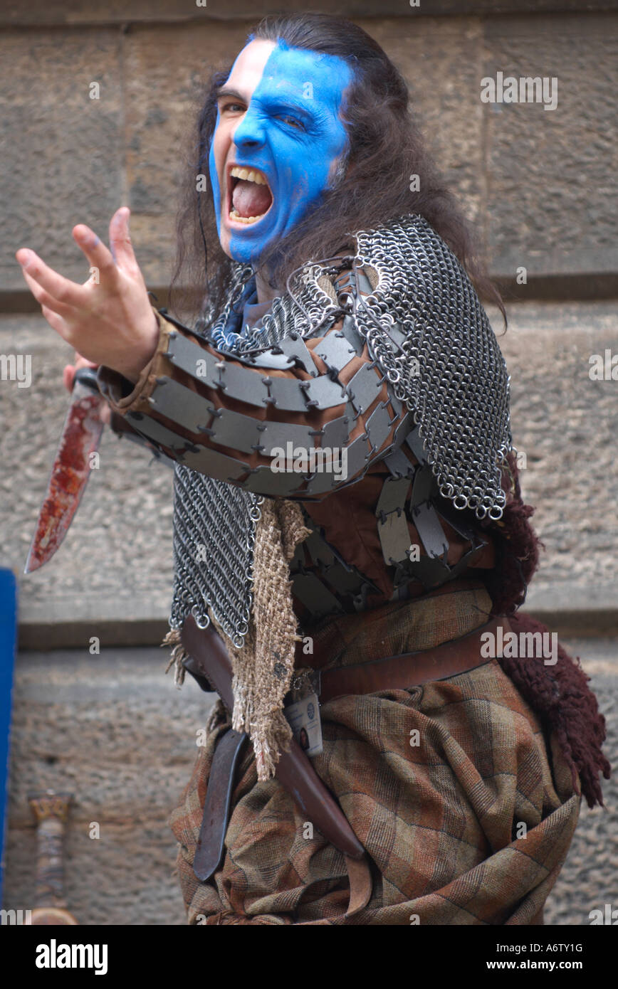 Street actor in medieval costume and face painted in scottish flag ...