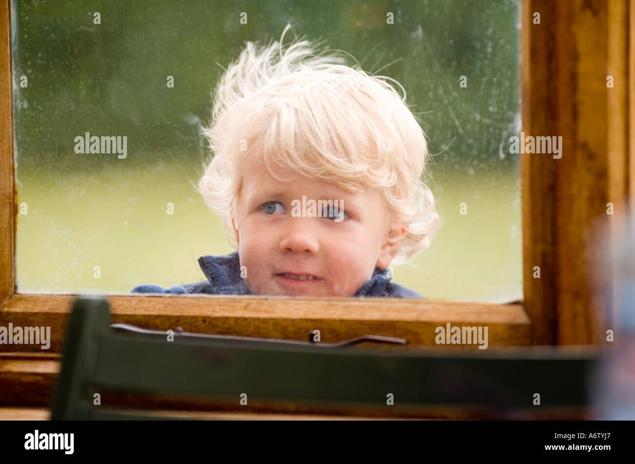 Young boy looking in window Stock Photo - Alamy