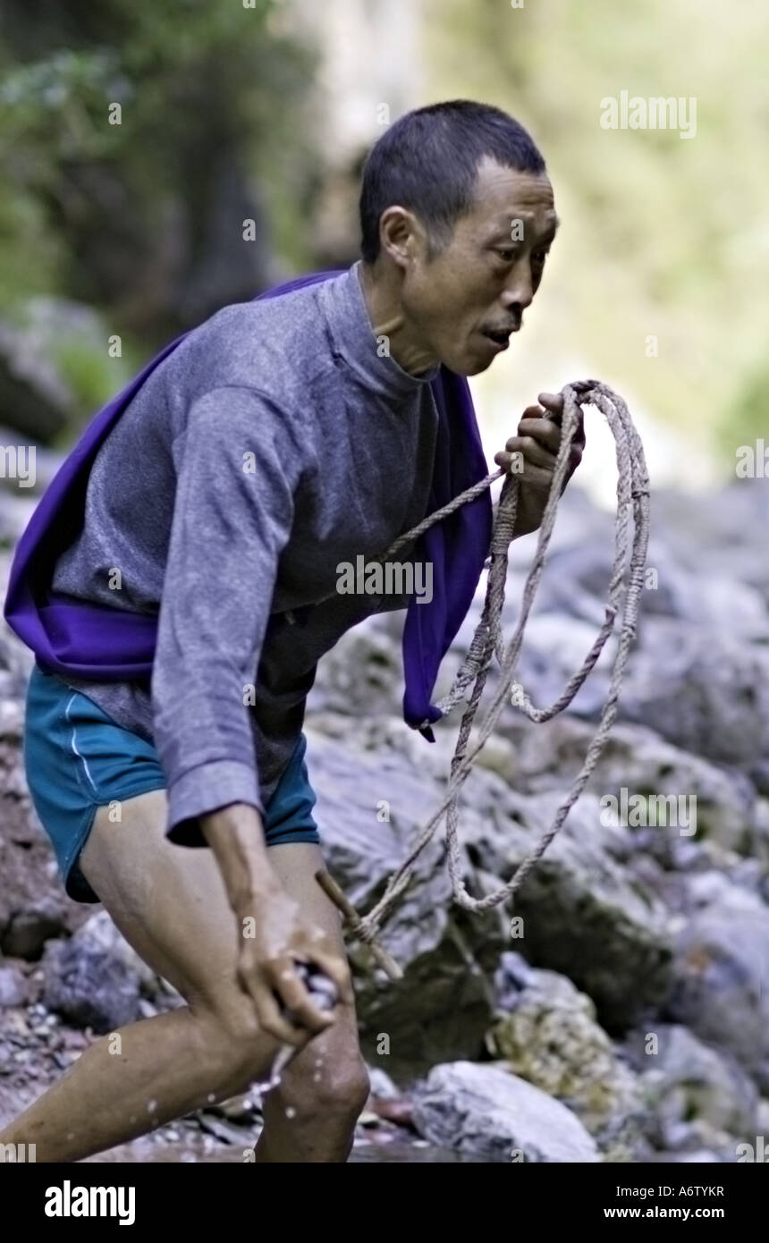 CHINA YANGTZE RIVER A boatmen who has been using ropes to pull pea ...