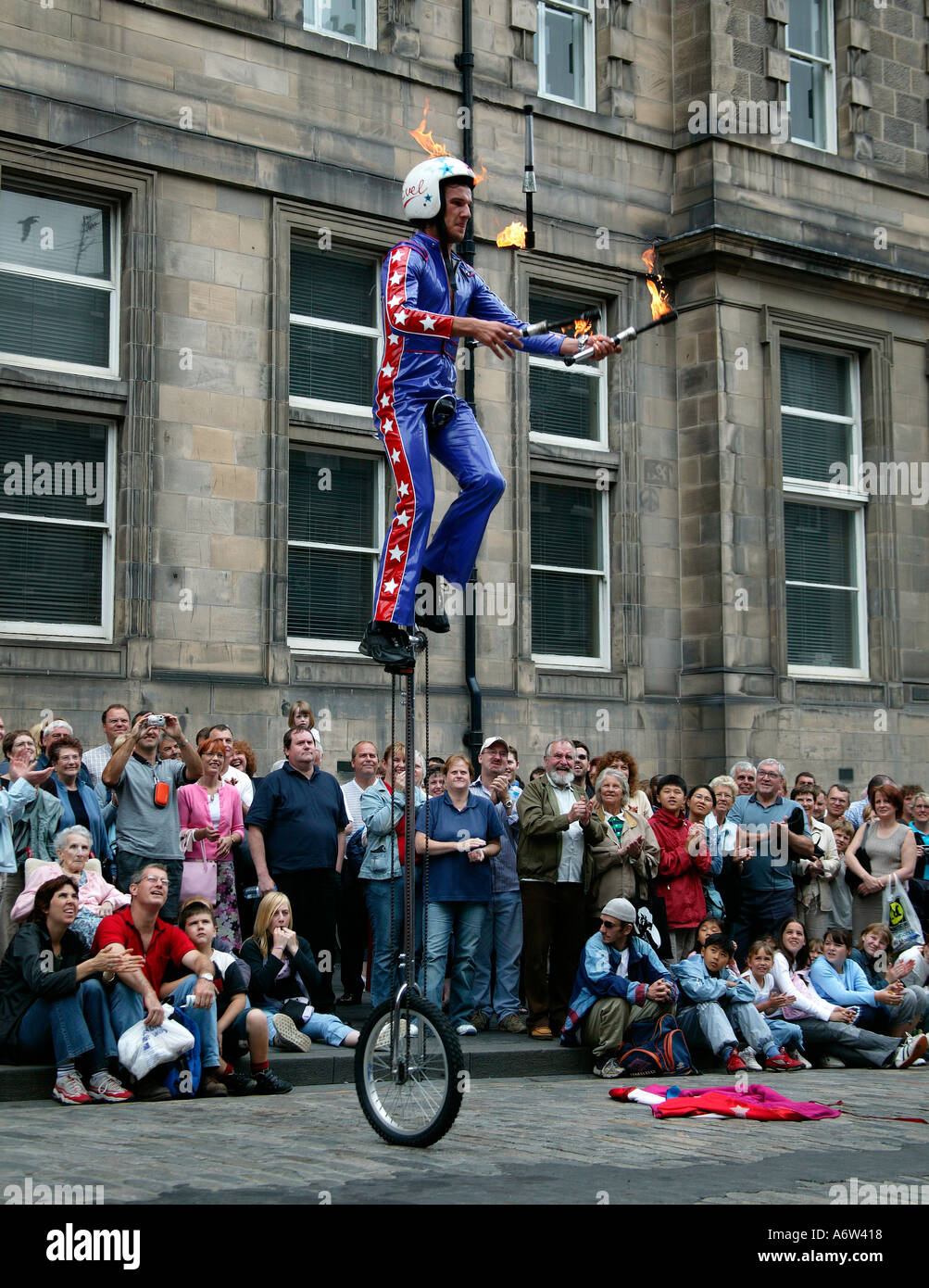 Male Street Performer performing on a unicycle while juggling fire ...