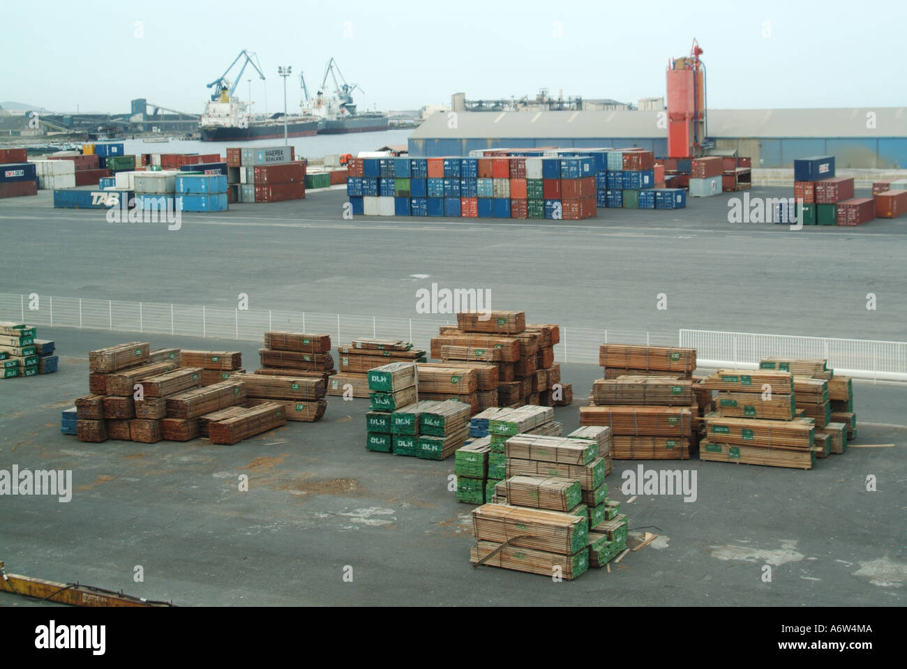 Sete port stacks of timber and containers on dockside shipping beyond ...