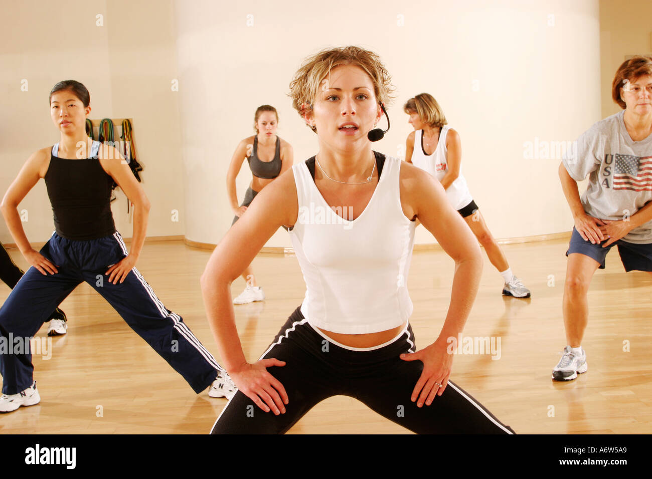 a kickboxing or aerobics class in a studio led by a blonde female ...