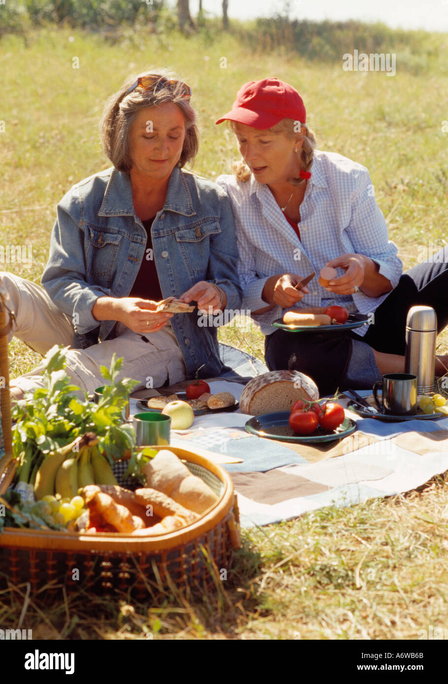 Two mature women sharing a picnic Stock Photo - Alamy