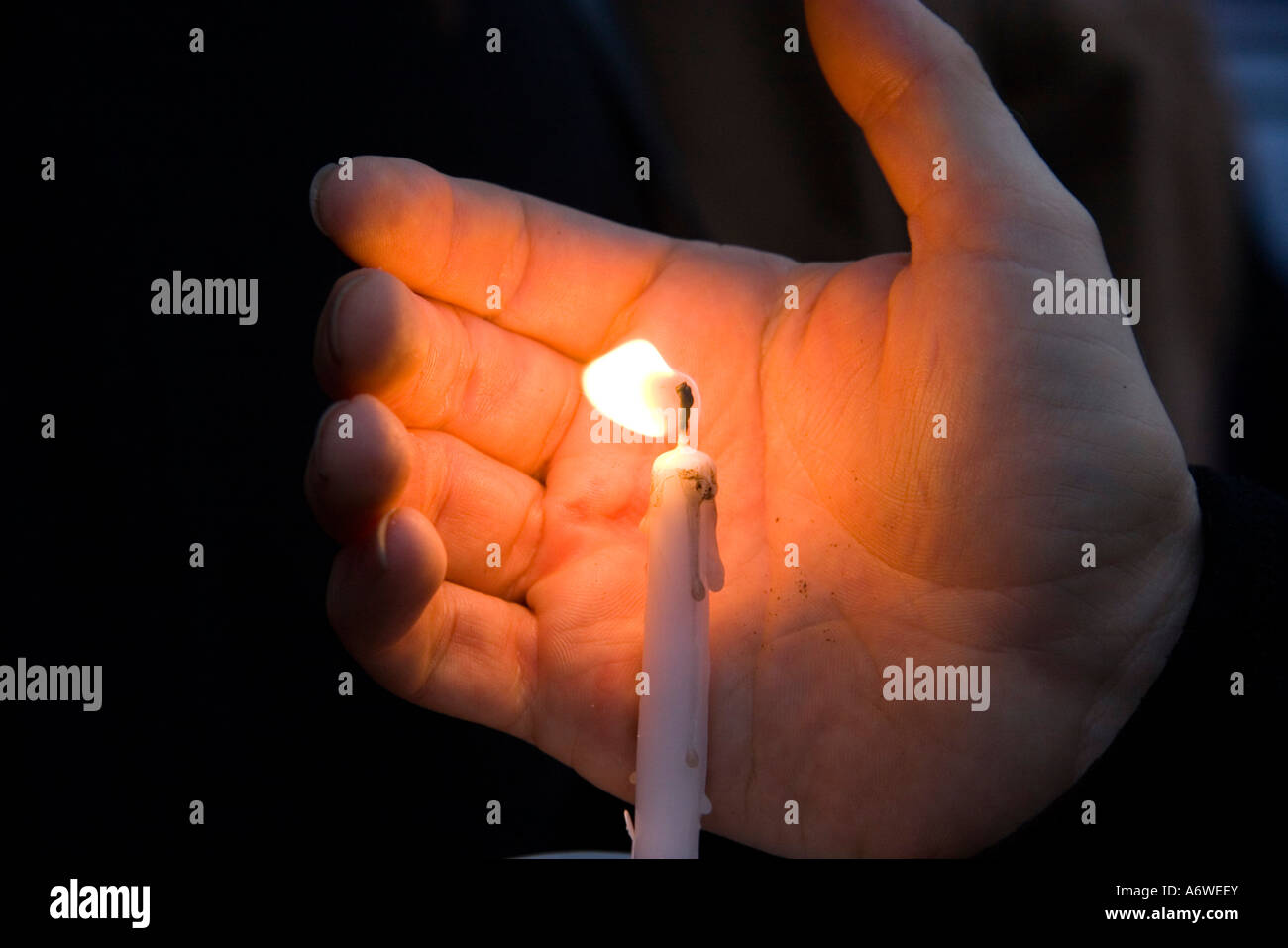 A hand shielding a candle during a candlelight vigil Stock Photo - Alamy