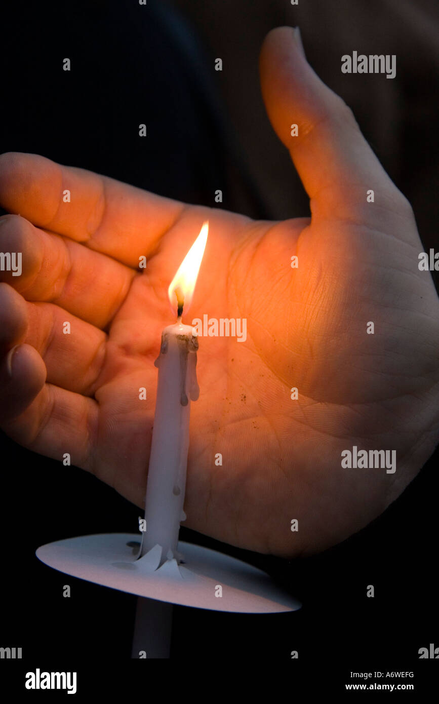 A hand shielding a candle during a candlelight vigil Stock Photo - Alamy
