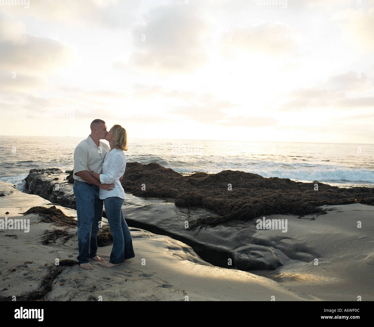 Couple holding each other on beach at sunset Stock Photo - Alamy