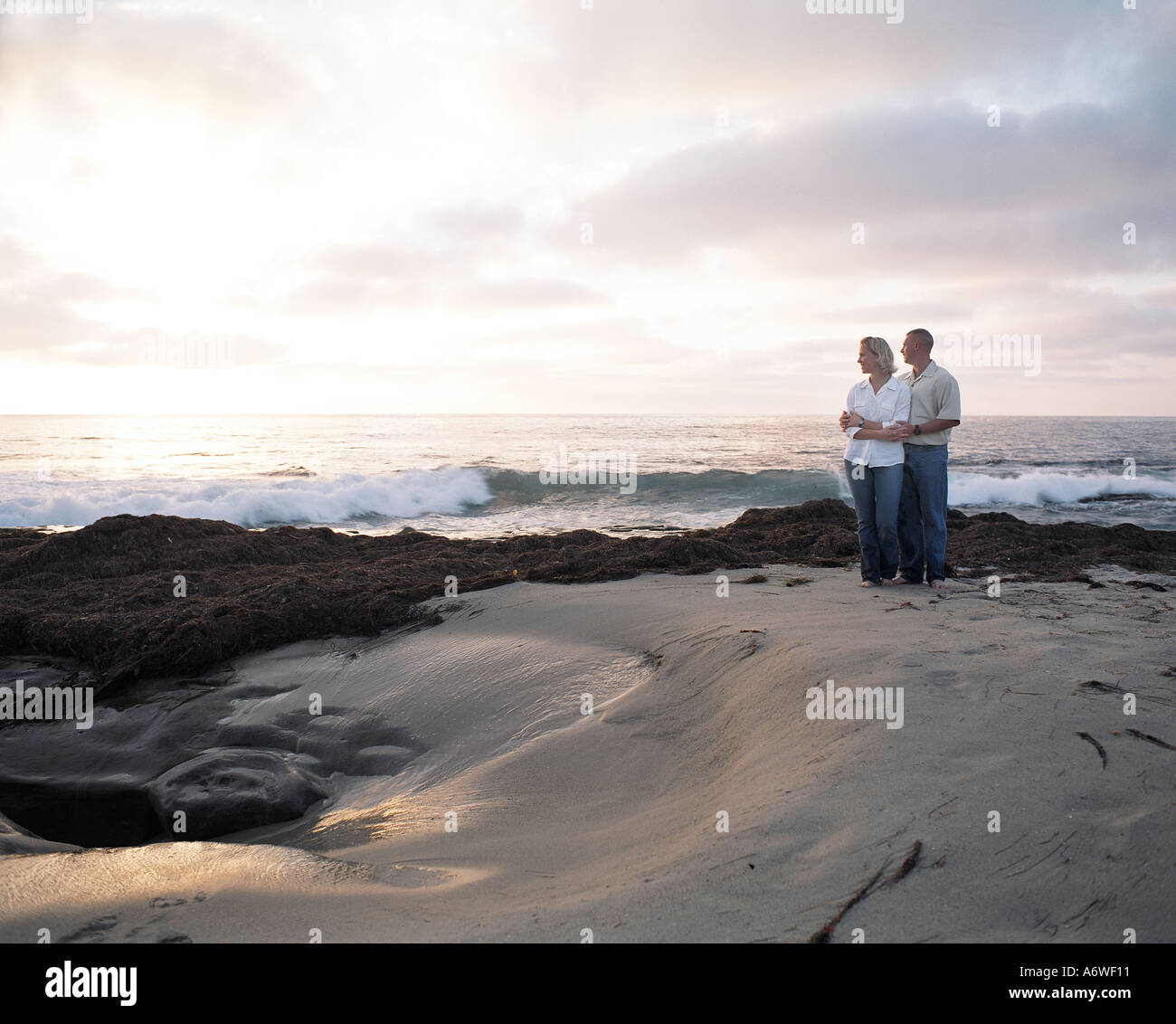 Couple holding each other on beach at sunset Stock Photo - Alamy