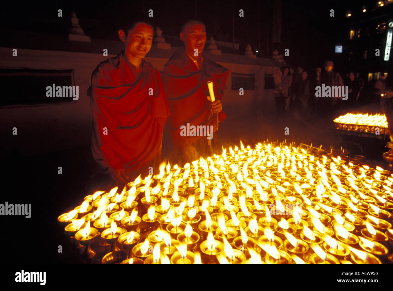 Asia, Nepal, Kathmandu. Buddhist Monks lighting candles at Bouddhanath ...