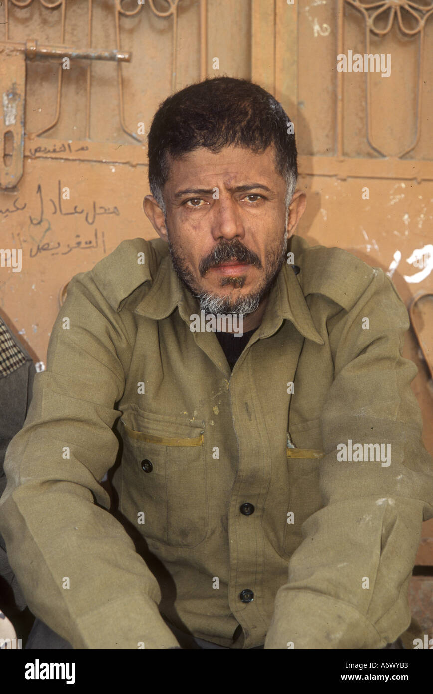 Yemen, Sana'a Yemeni man in western work clothes in front of graffitied ...