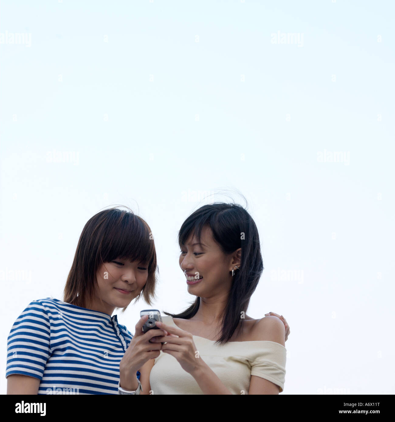 Two young women using cell phone Stock Photo - Alamy