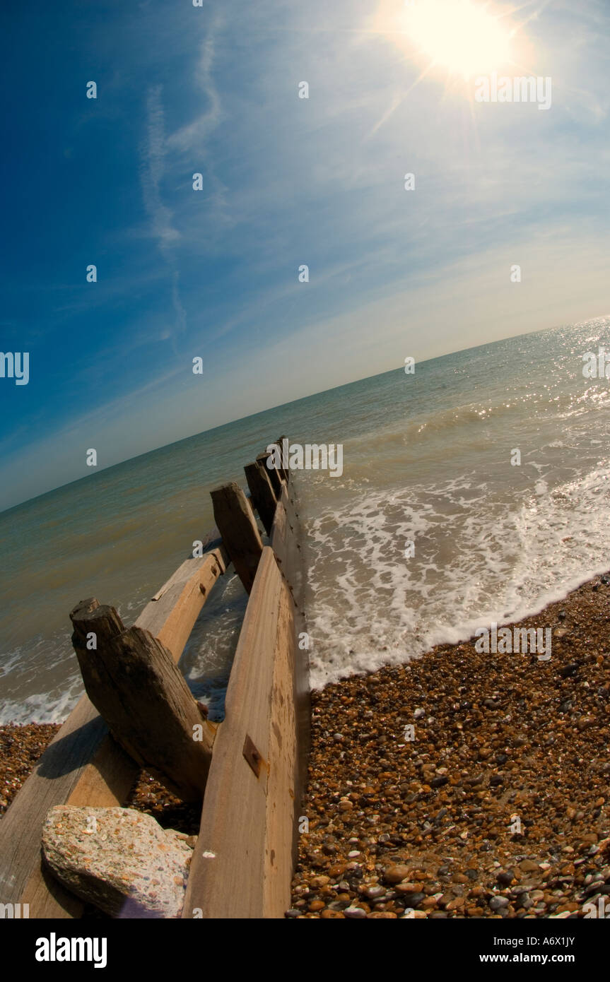 shoreline with wood groin, sun and blue sky Stock Photo - Alamy