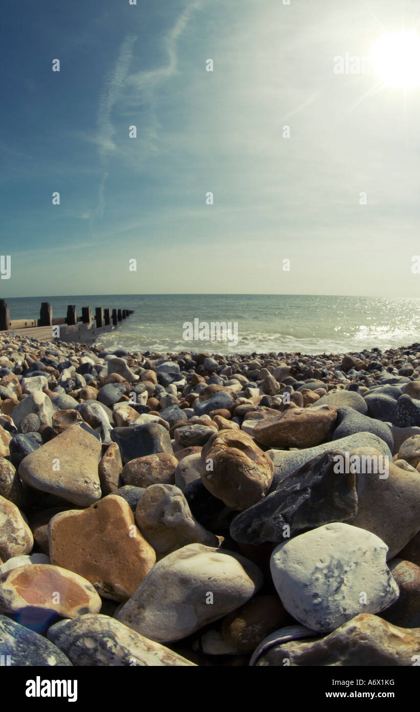 shingle beach with sun and blue sky Stock Photo - Alamy