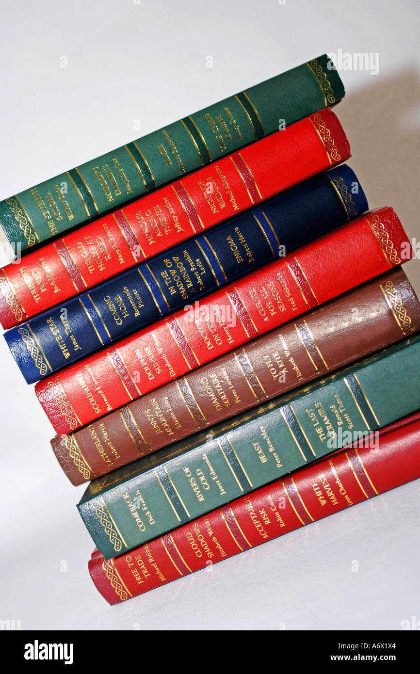 A Vertical stack of colored leather bound books against a white ...