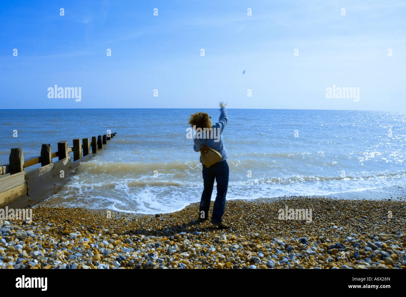 woman throwing a stone into the sea Stock Photo - Alamy