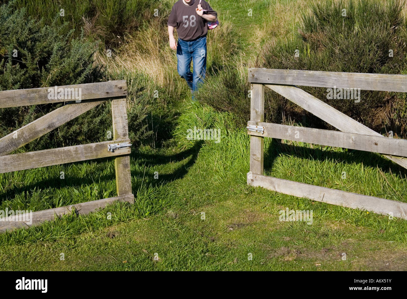 An unrecognizable man walking through a gate on a hiking trail at Spey ...