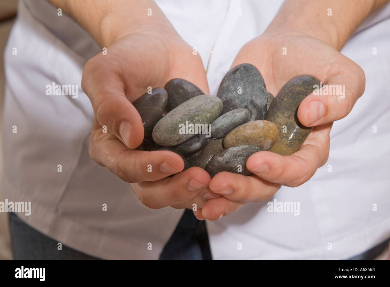A female massage therapist holding stones for hot stone therapy Stock ...