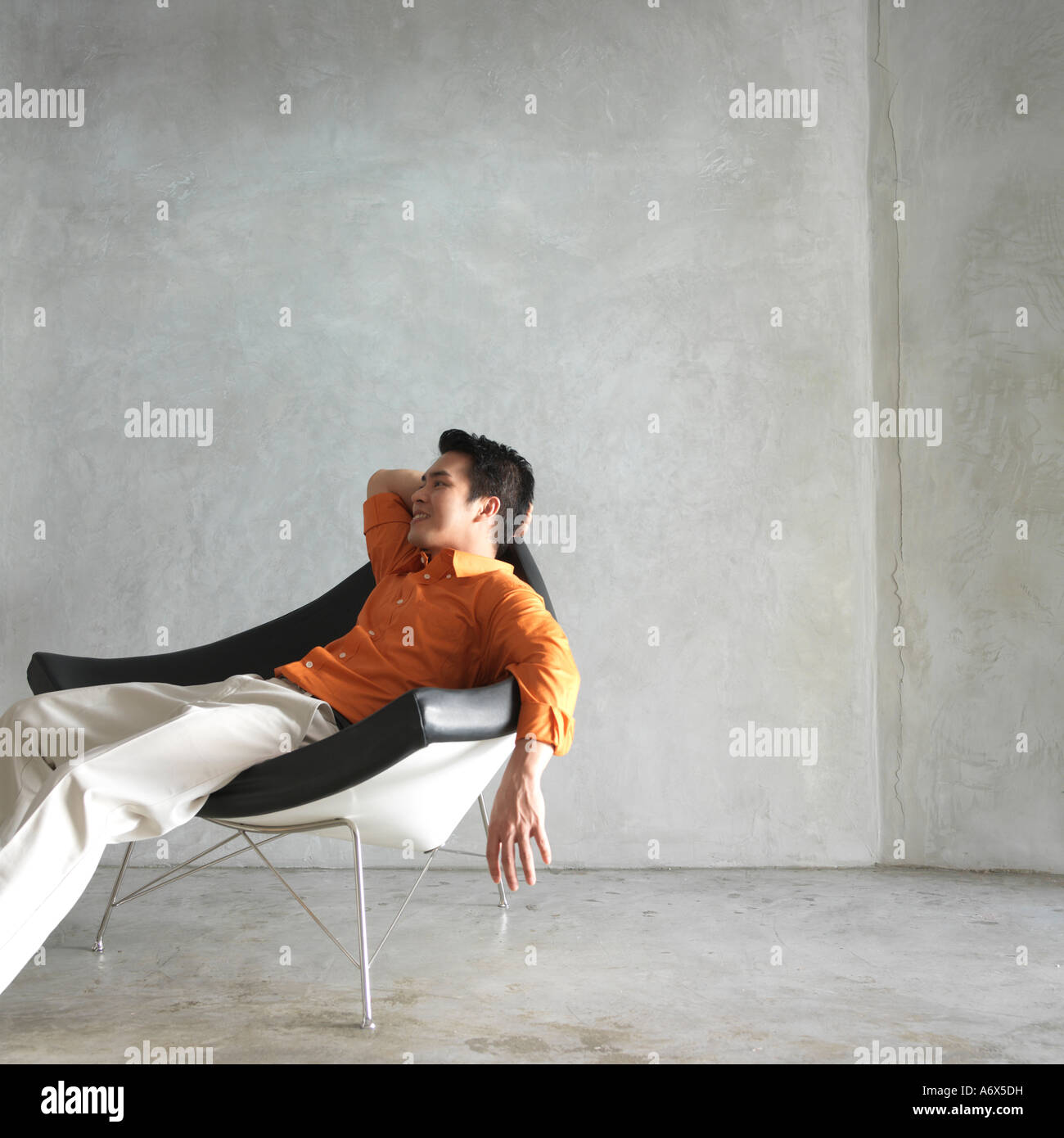 Man relaxing on chair, arm behind head Stock Photo - Alamy