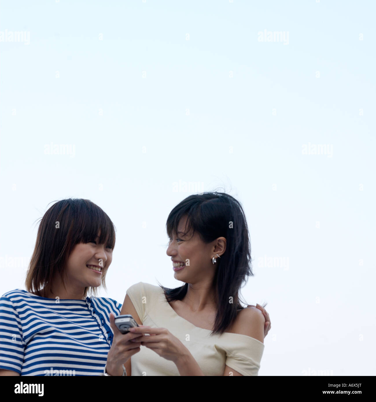 Two young women using cell phone Stock Photo - Alamy