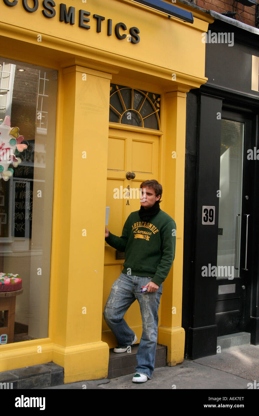man opening yellow front door inbetween shops in london uk Stock Photo ...