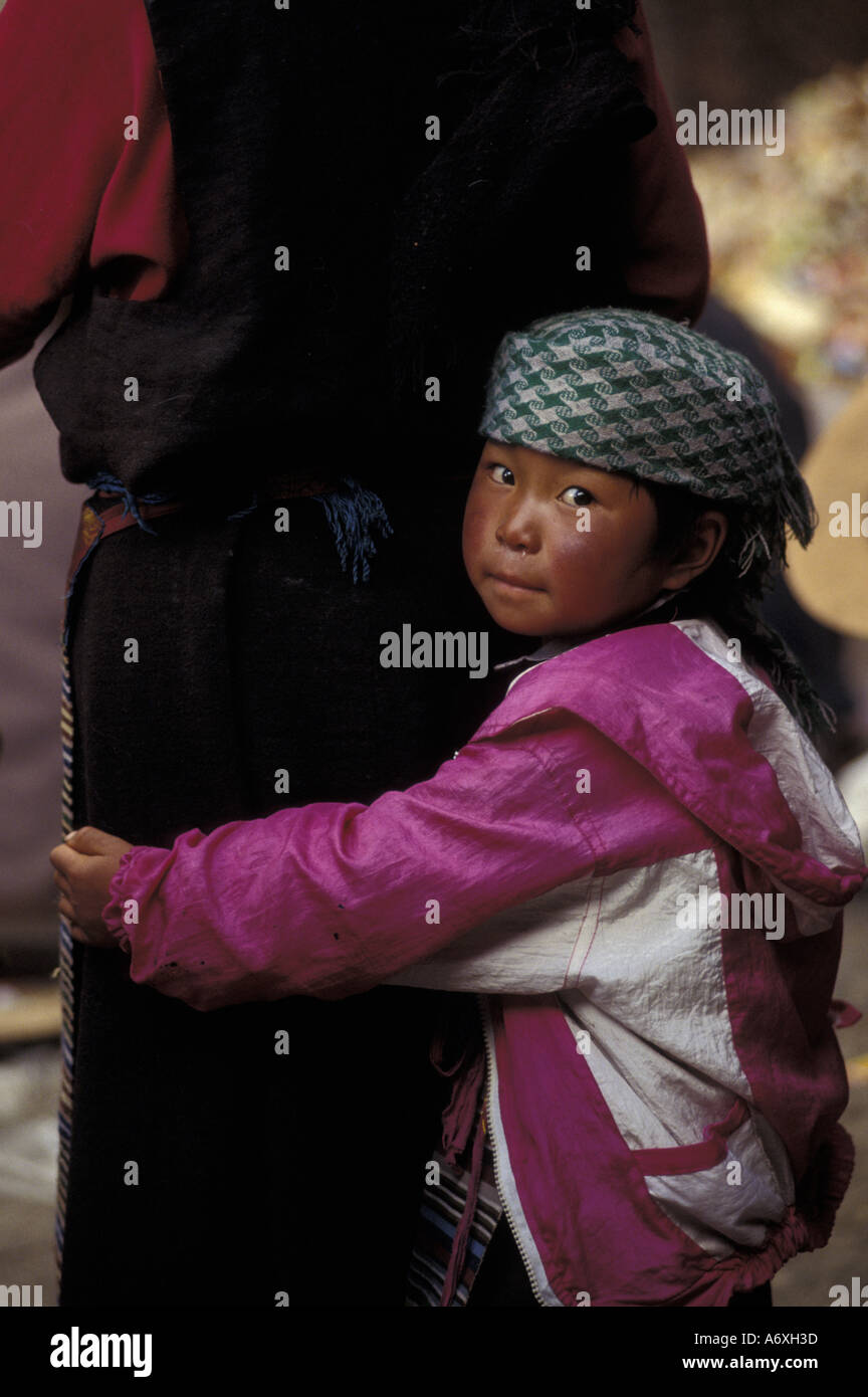 Asia, Tibet, Lhasa A Tibetan girl clings to her mother's skirt Stock ...