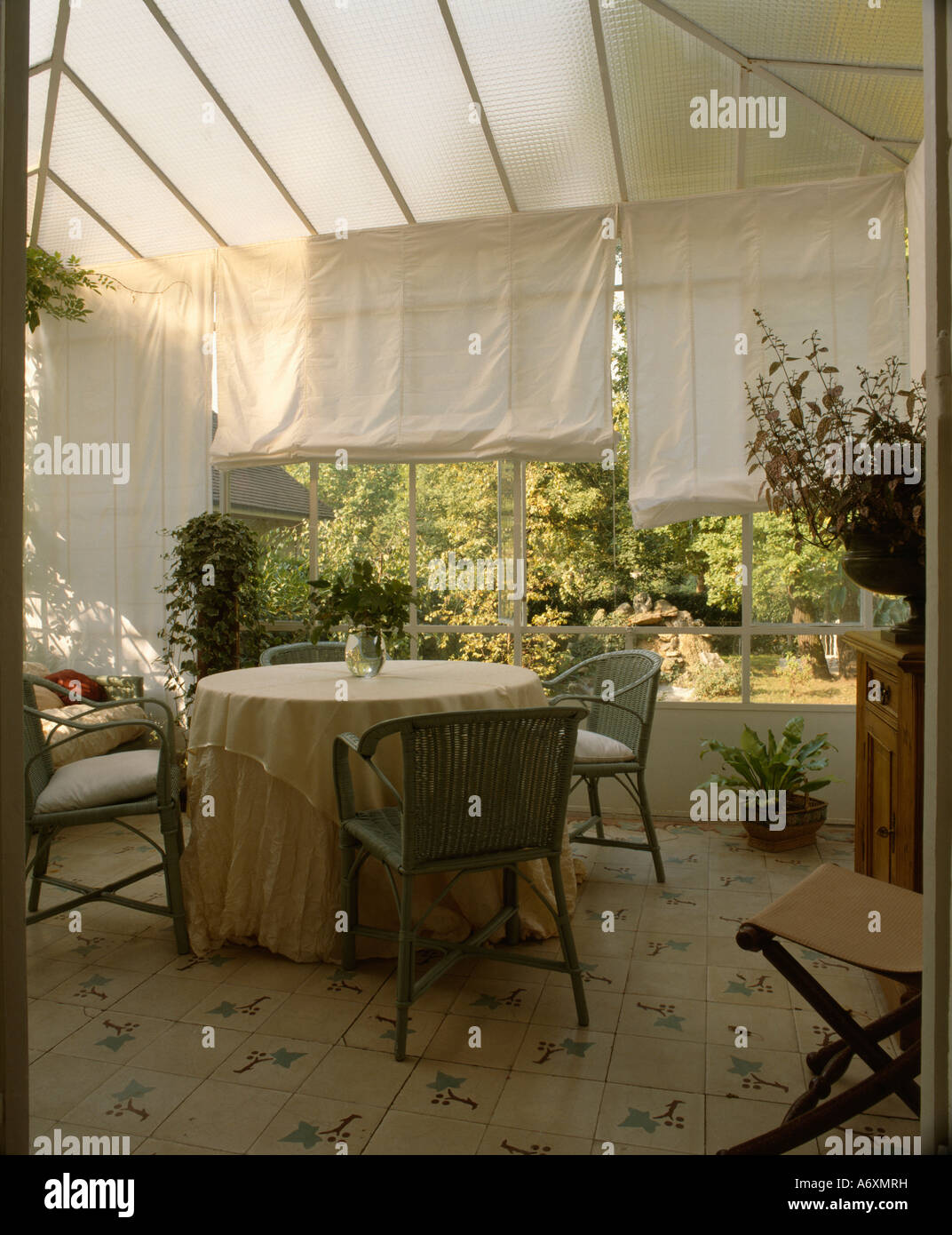 Dining table in traditional conservatory with white cotton blinds and ...