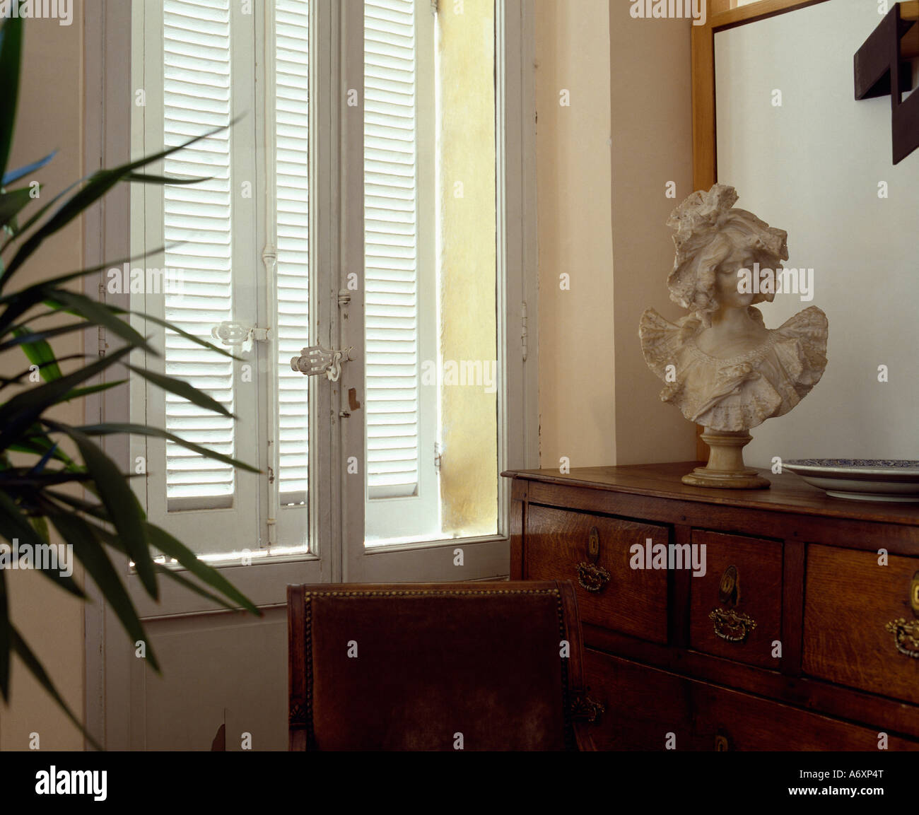 Classical marble bust on antique chest-of-drawers in front of window ...