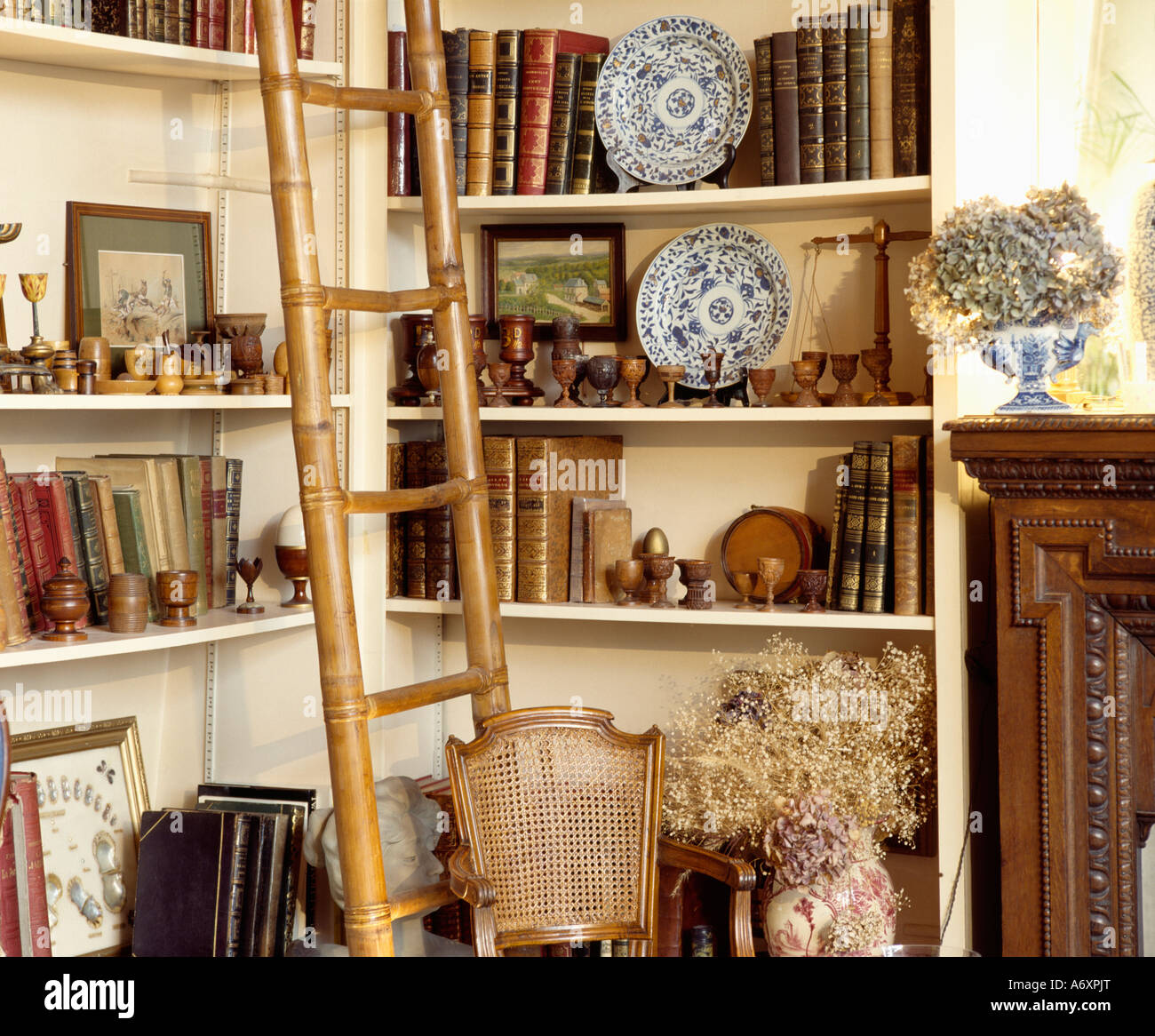 Bamboo ladder against shelves with books and plates in corner of ...