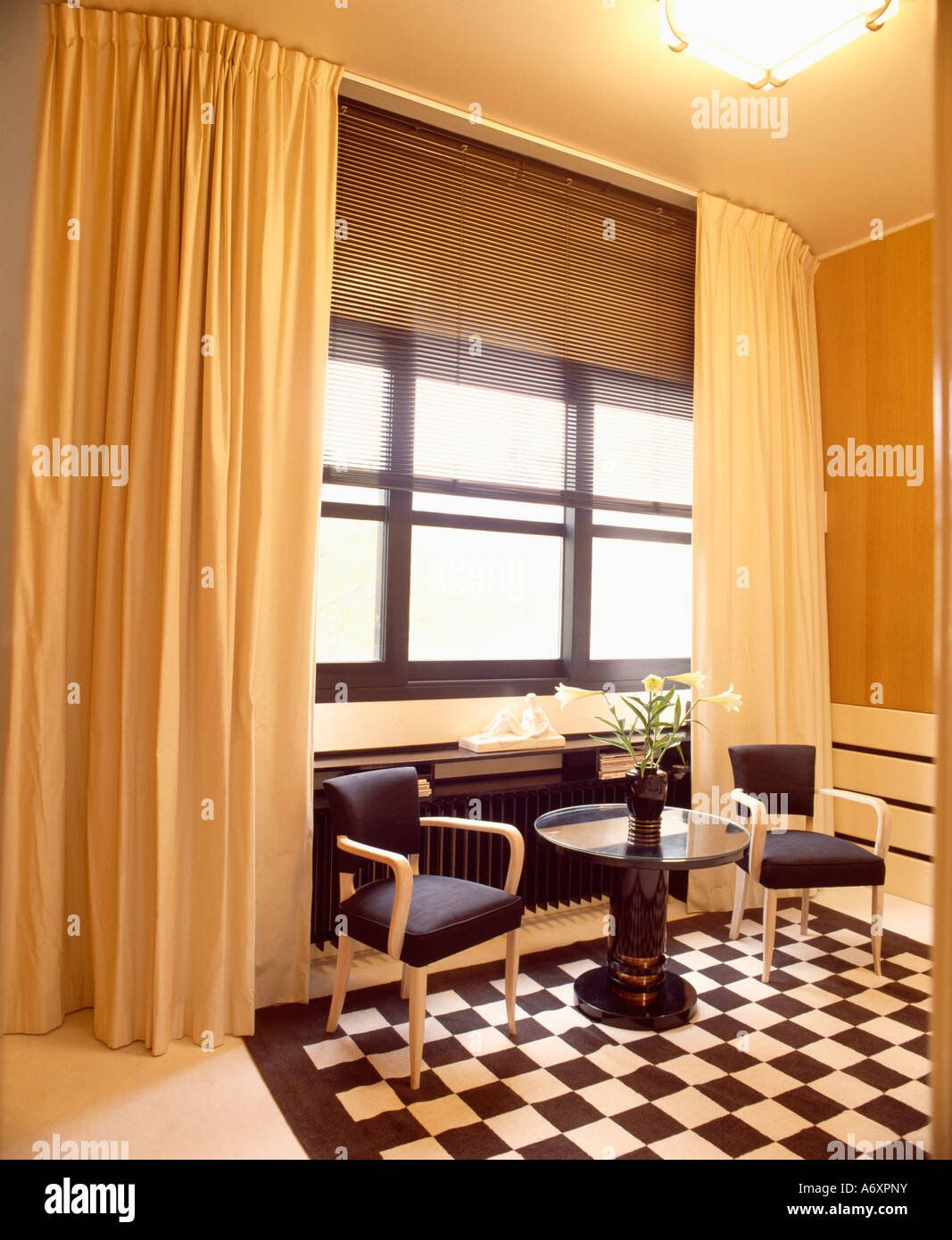 Black and white chequerboard rug in front of window with cream drapes ...