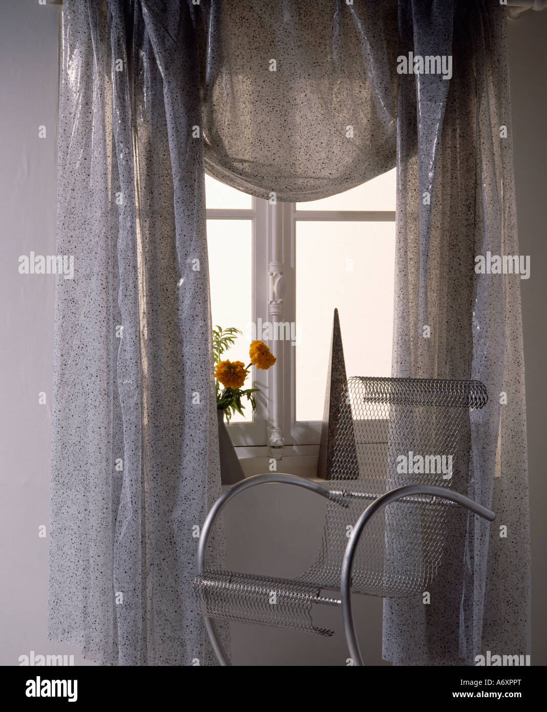 Chrome chair in front of window with metallic grey drapes and blind ...