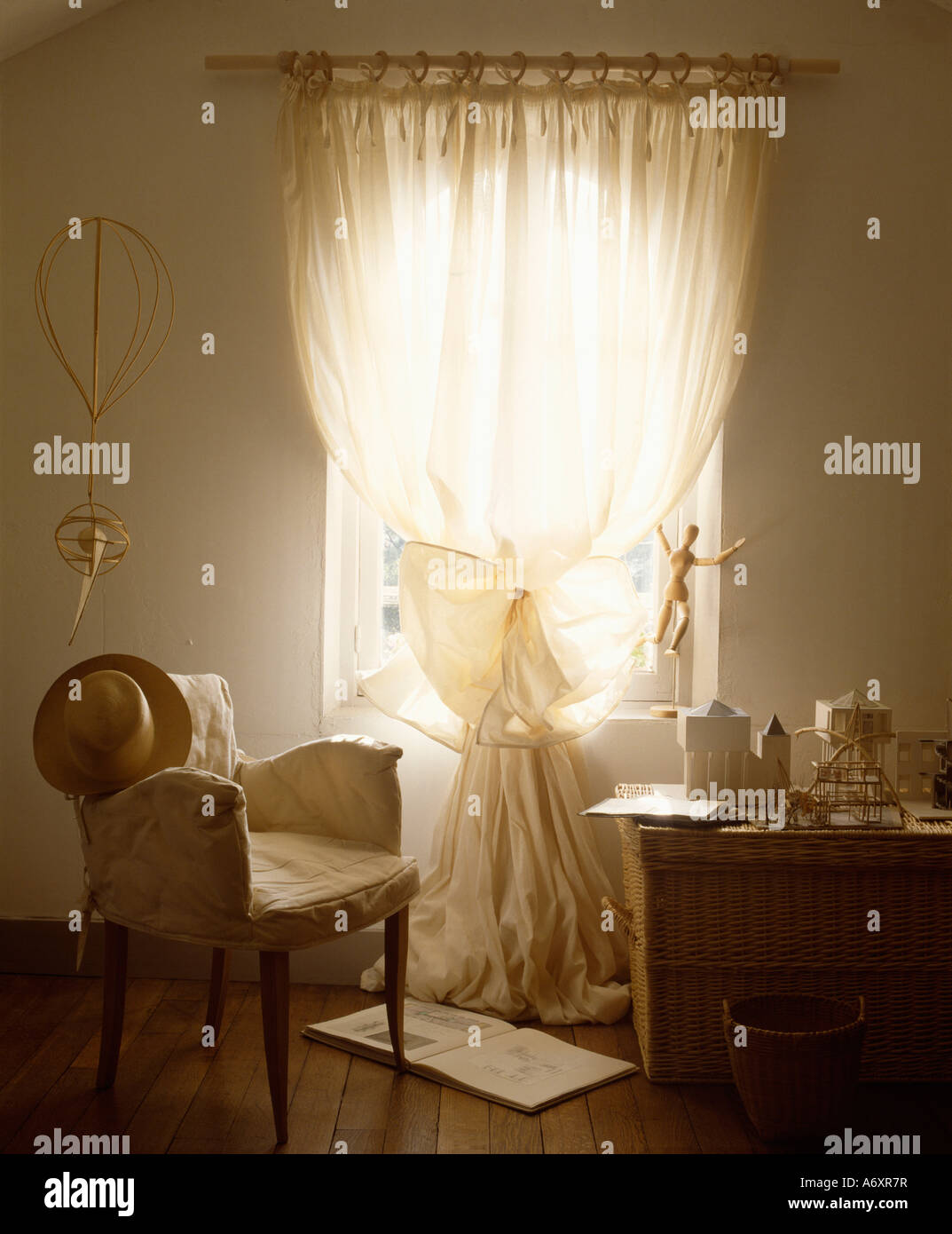 Chair with cotton loosecover in front of window with sheer muslin ...