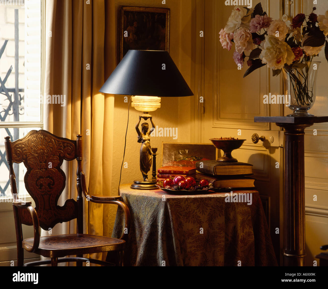 Antique chair beside table with cloth and lighted lamp Stock Photo - Alamy