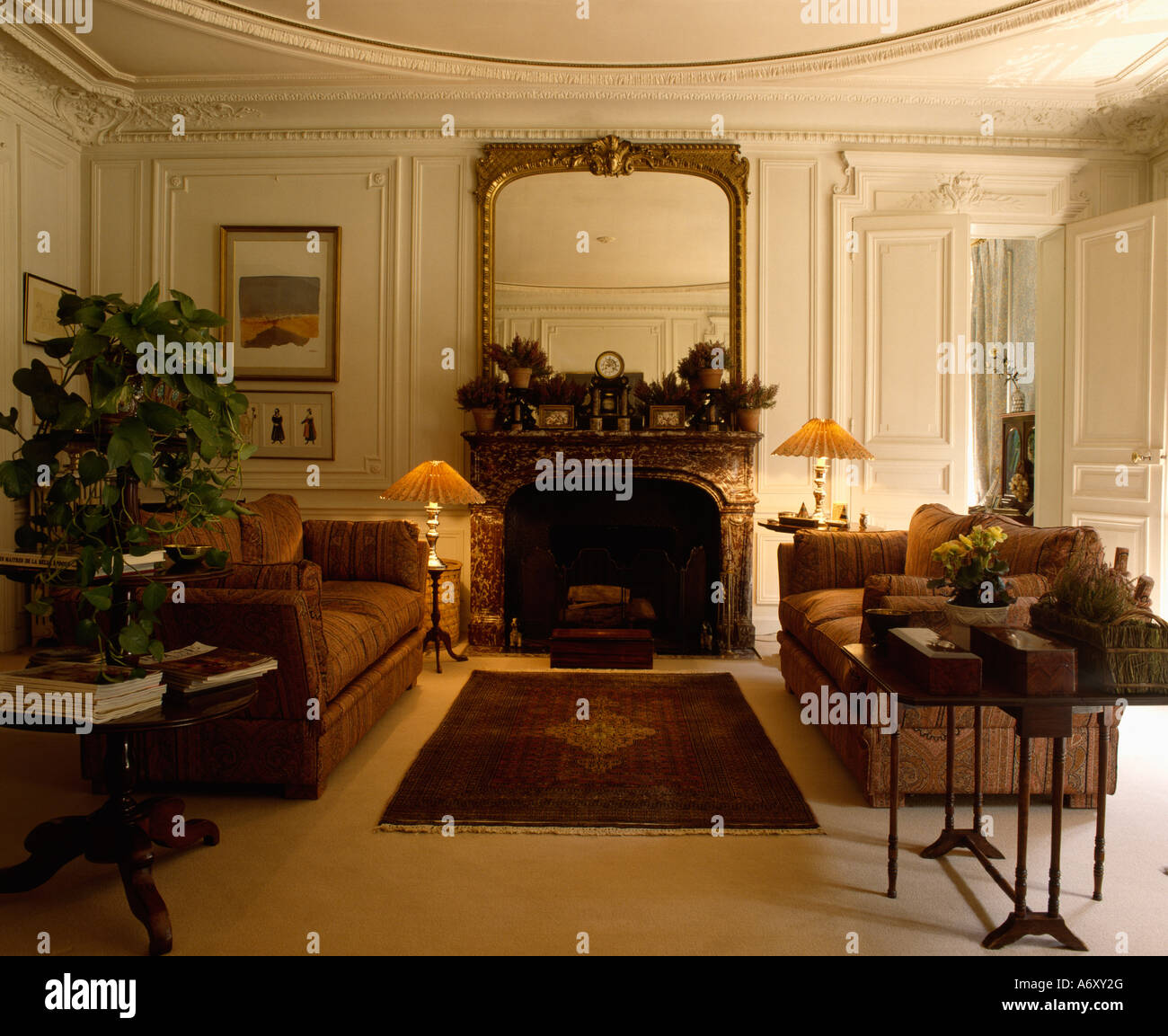 Cream panelled sittingroom with mirror above fireplace and two settees ...