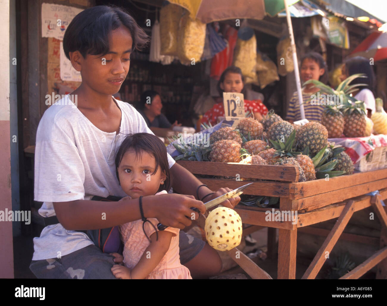 Philippines market stall a father prepares a pineapple for his stall ...
