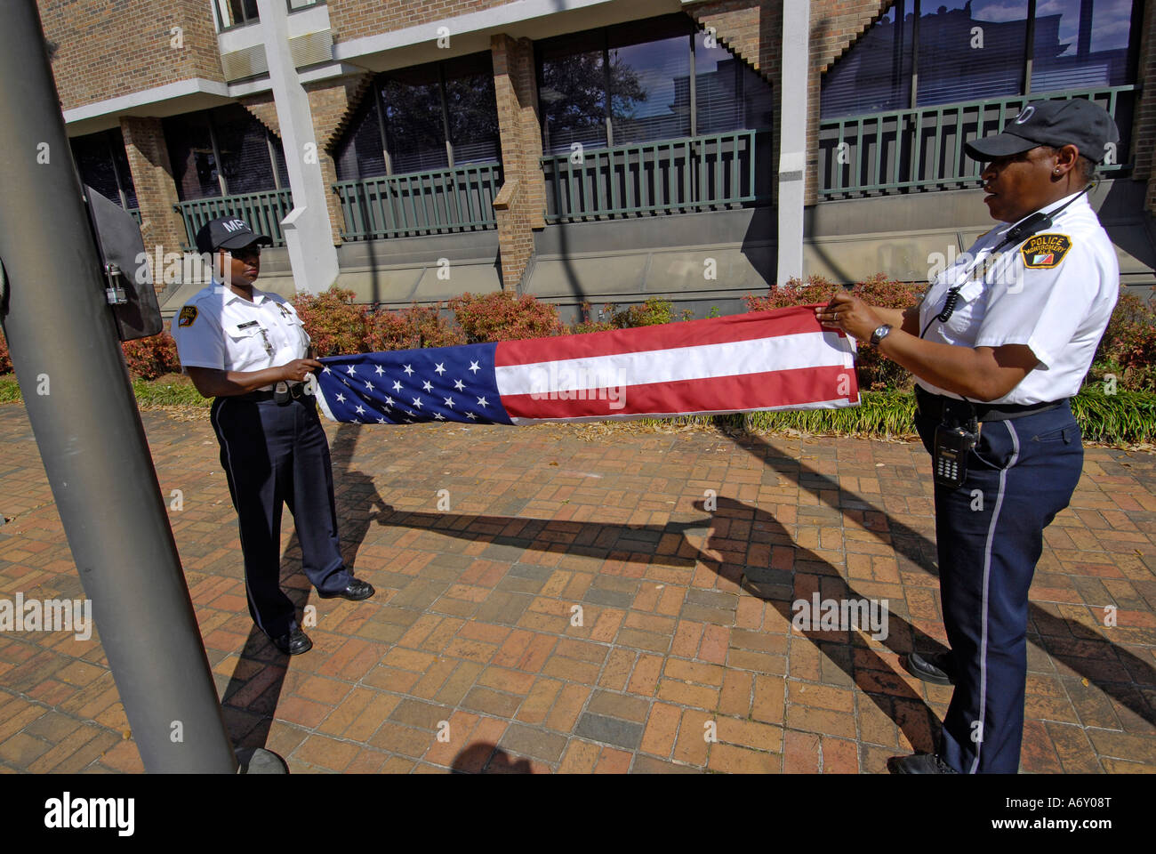 Black female police officers take the America flag down a fold it at ...