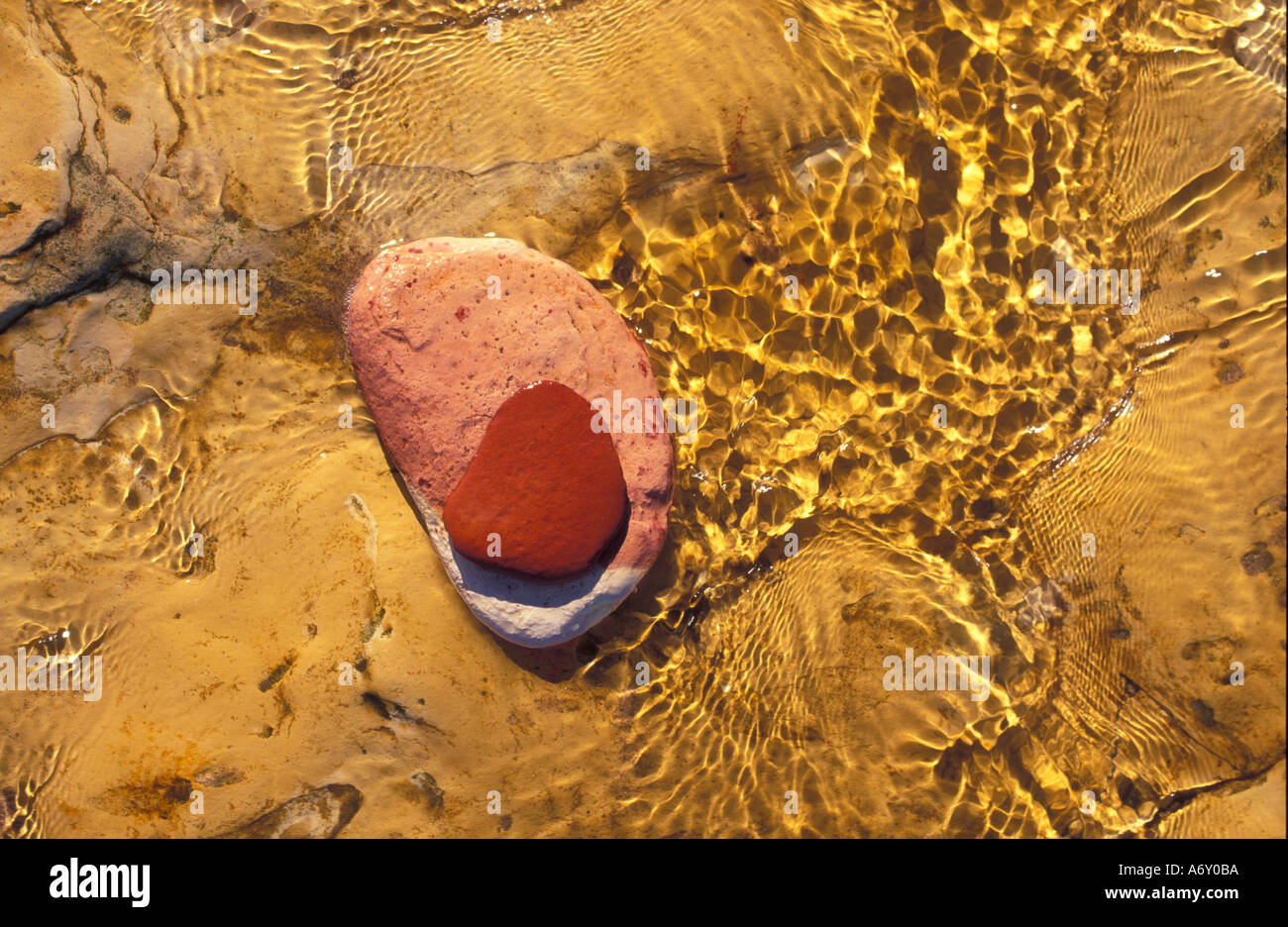 Rock pool with reflecting sunlit water sea sand and stone shapes make ...