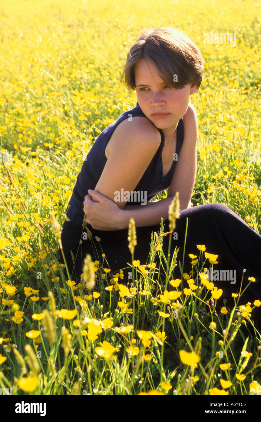 Teenage girl looking wistful sad and thoughtful alone in a field of ...