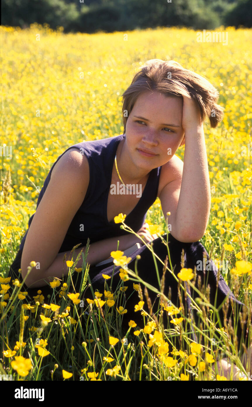 Teenage girl looking wistful sad and thoughtful alone in a field of ...
