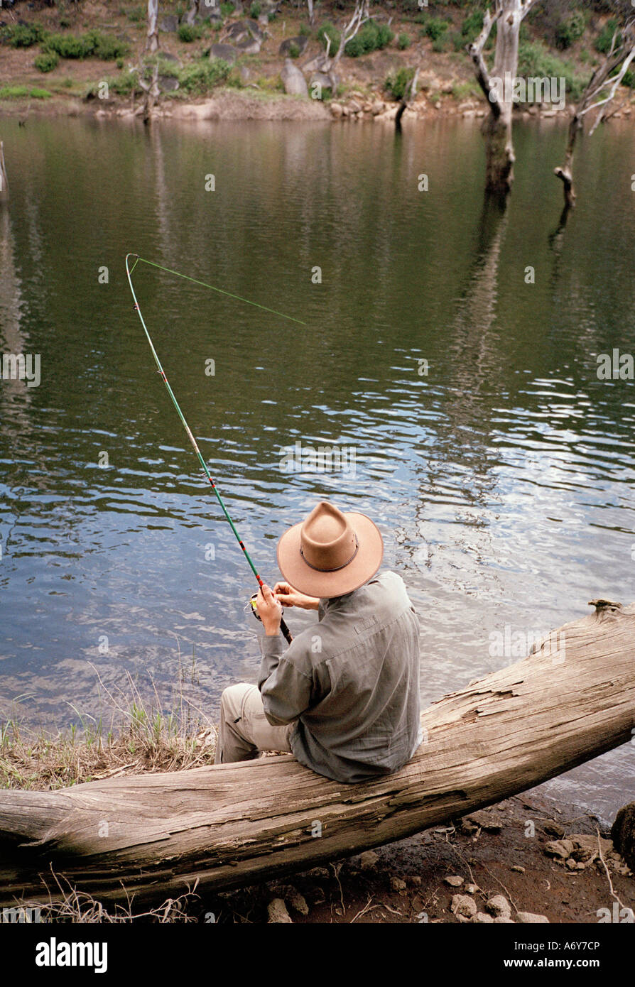 Man fishing from a log on a riverbank Stock Photo - Alamy