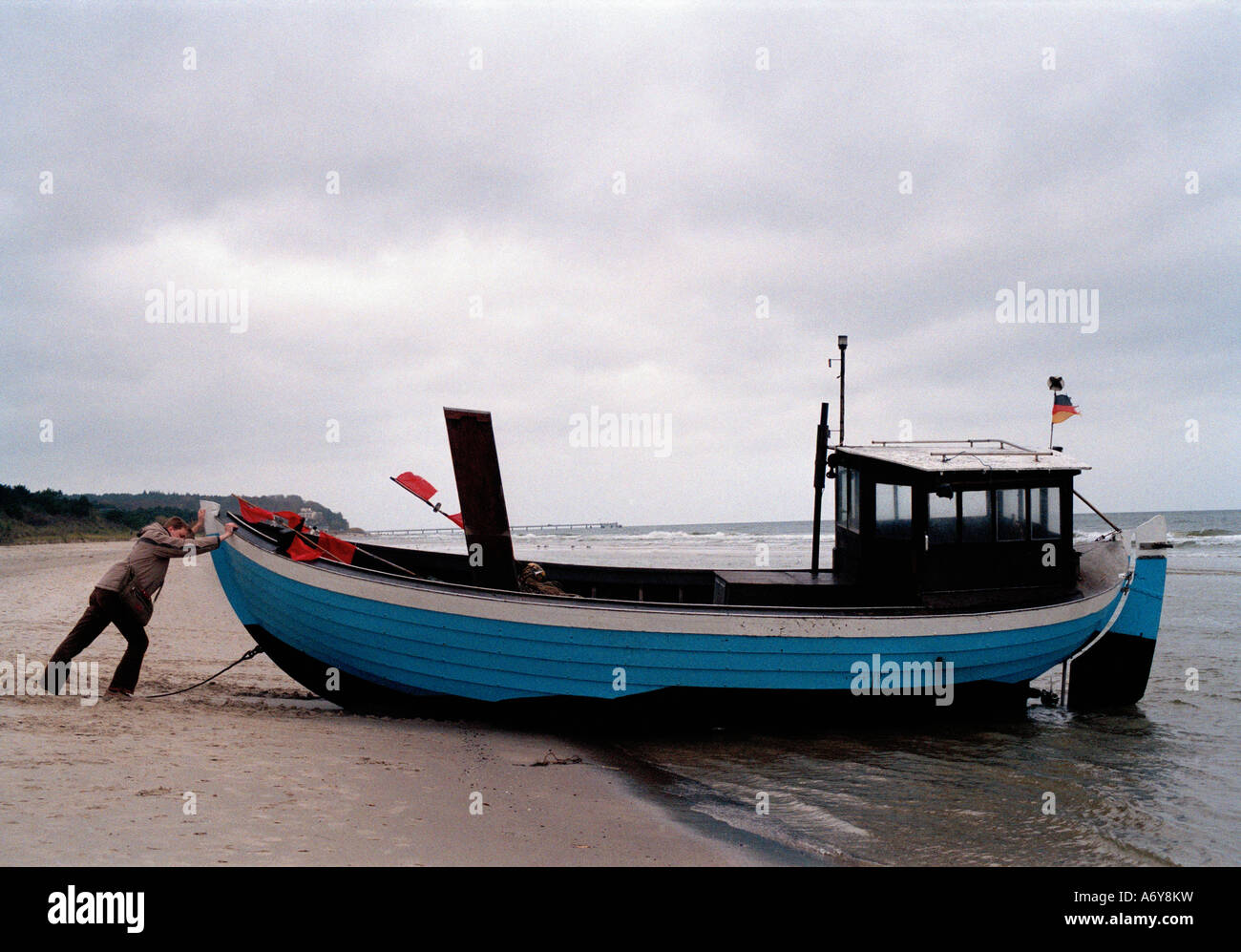 Man pushing a boat into the sea Stock Photo - Alamy