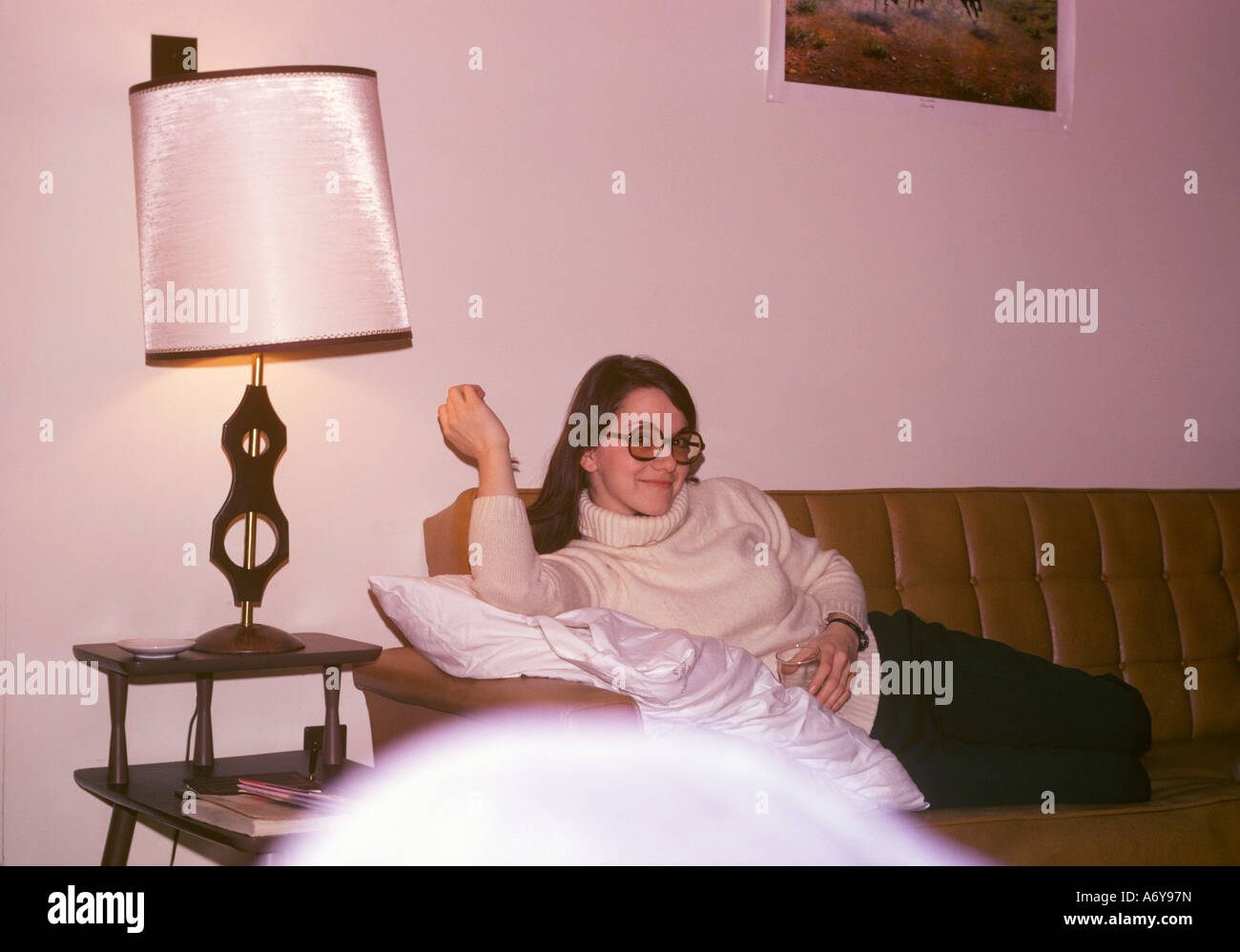 A woman reclining on a sofa in a living room Stock Photo - Alamy