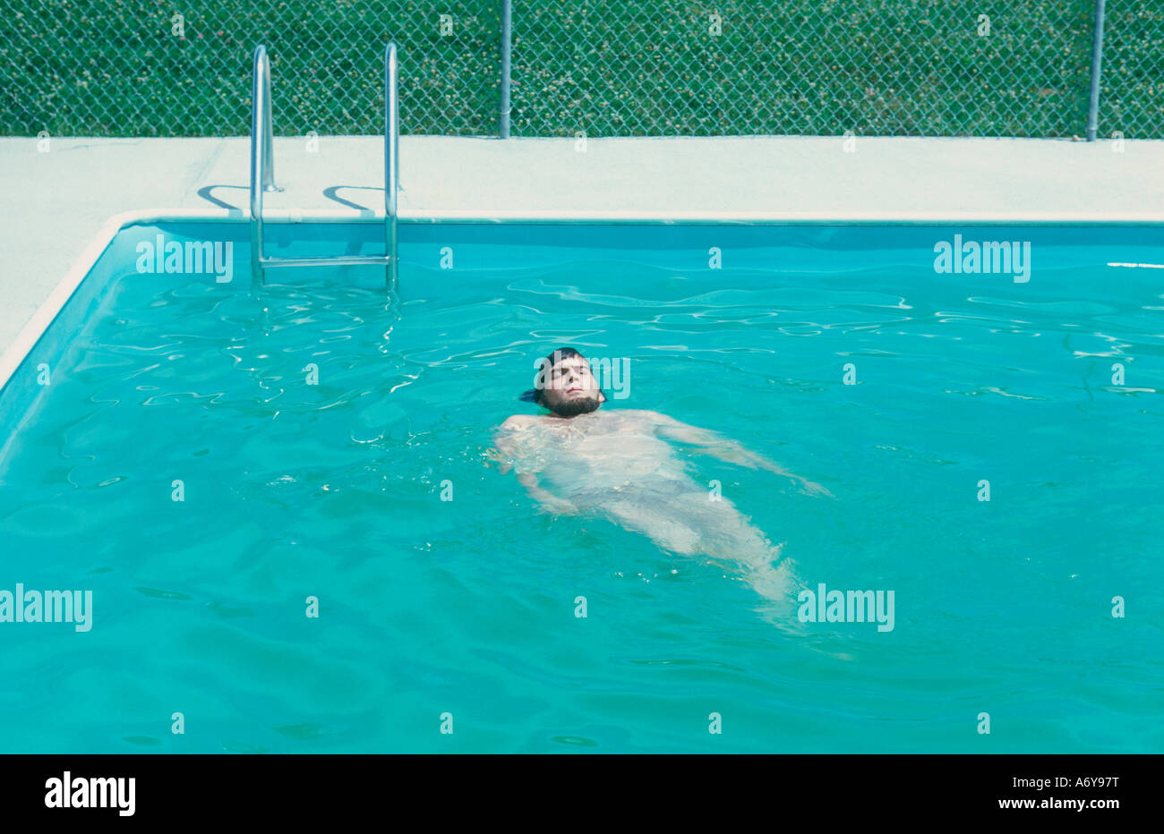 A man floating in an outdoor swimming pool Stock Photo - Alamy