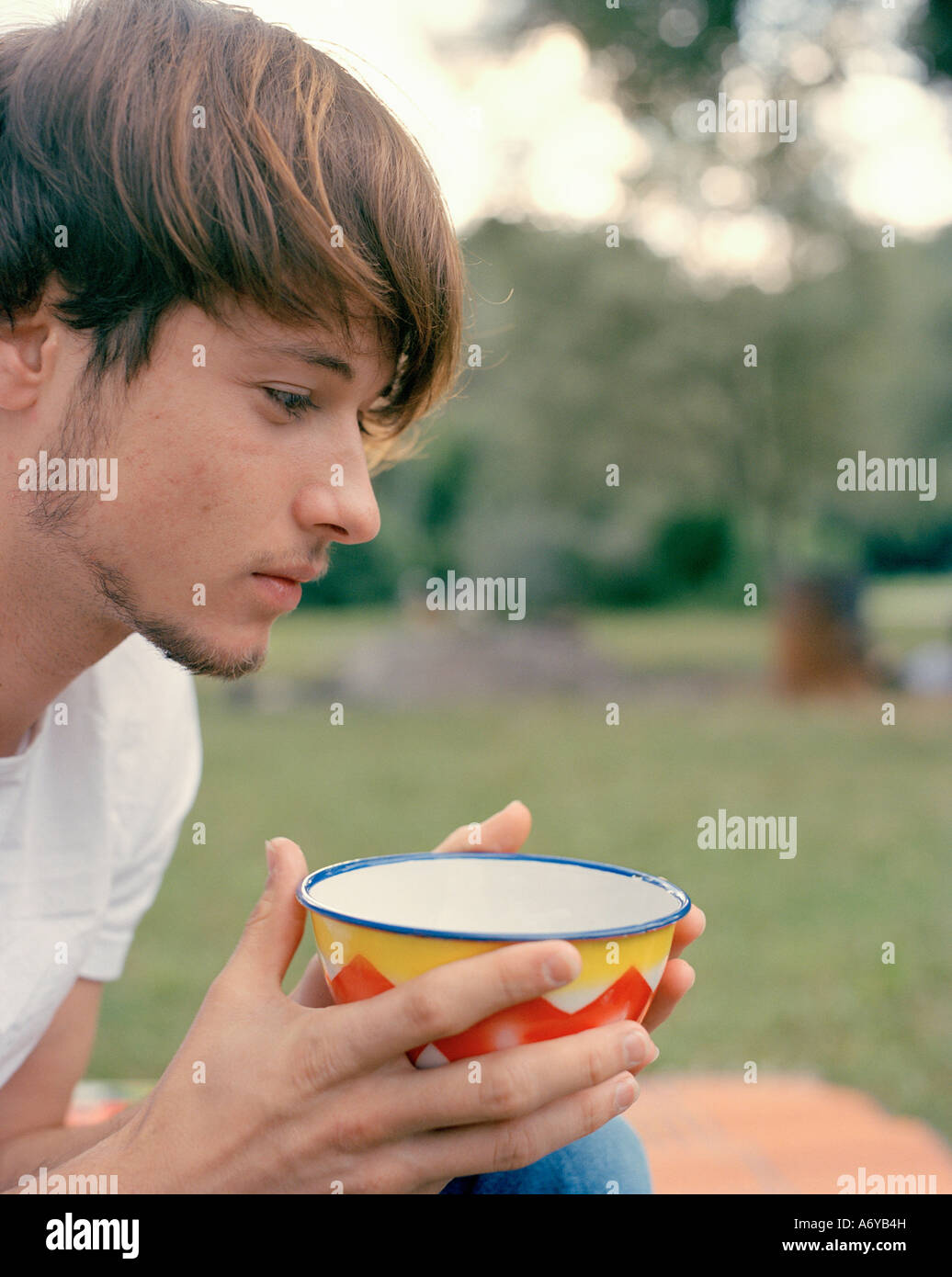 A young man drinking from a bowl Stock Photo - Alamy