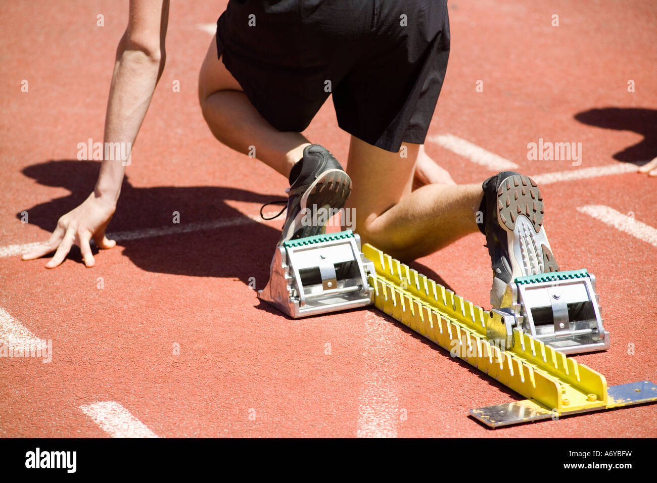 Male athlete in starting blocks on a running track Stock Photo - Alamy