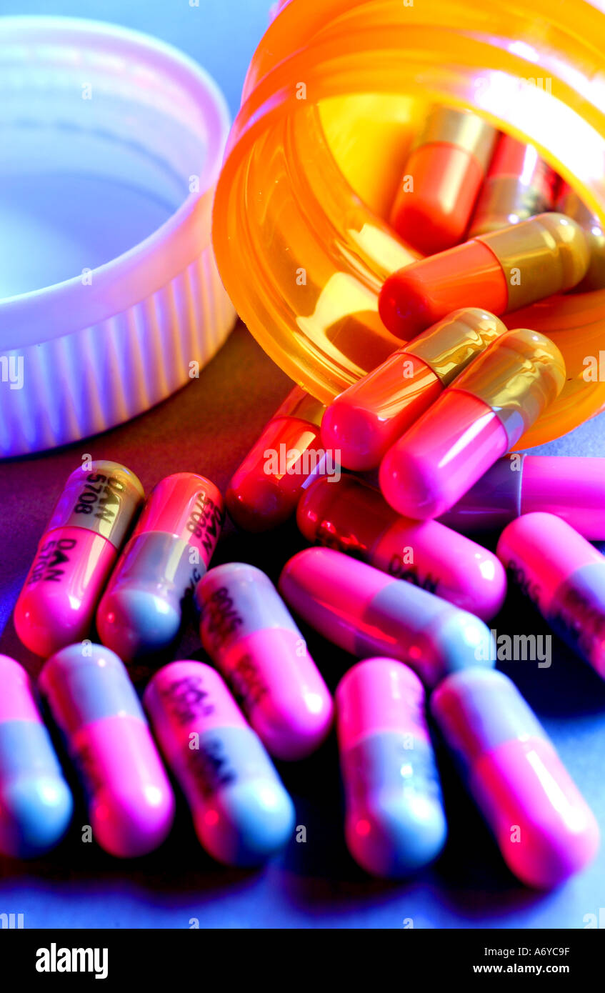 Vertical color image of capsules pouring from a yellow medicine bottle ...