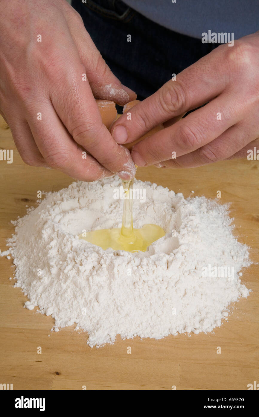 A man cracking an egg into a pile of flour Stock Photo - Alamy