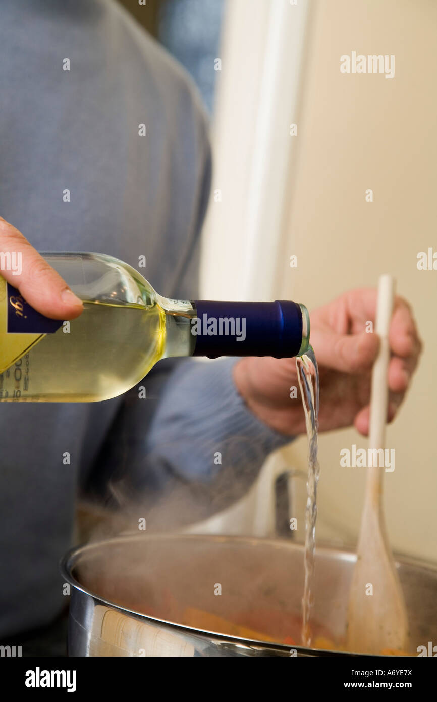 A man adding white wine to a saucepan Stock Photo - Alamy