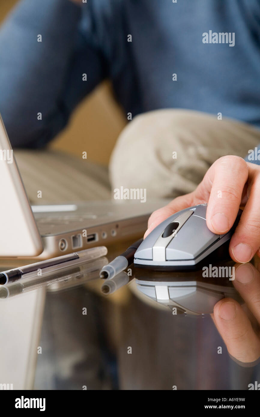 Man using a laptop with a mouse on a glass coffee table Stock Photo - Alamy