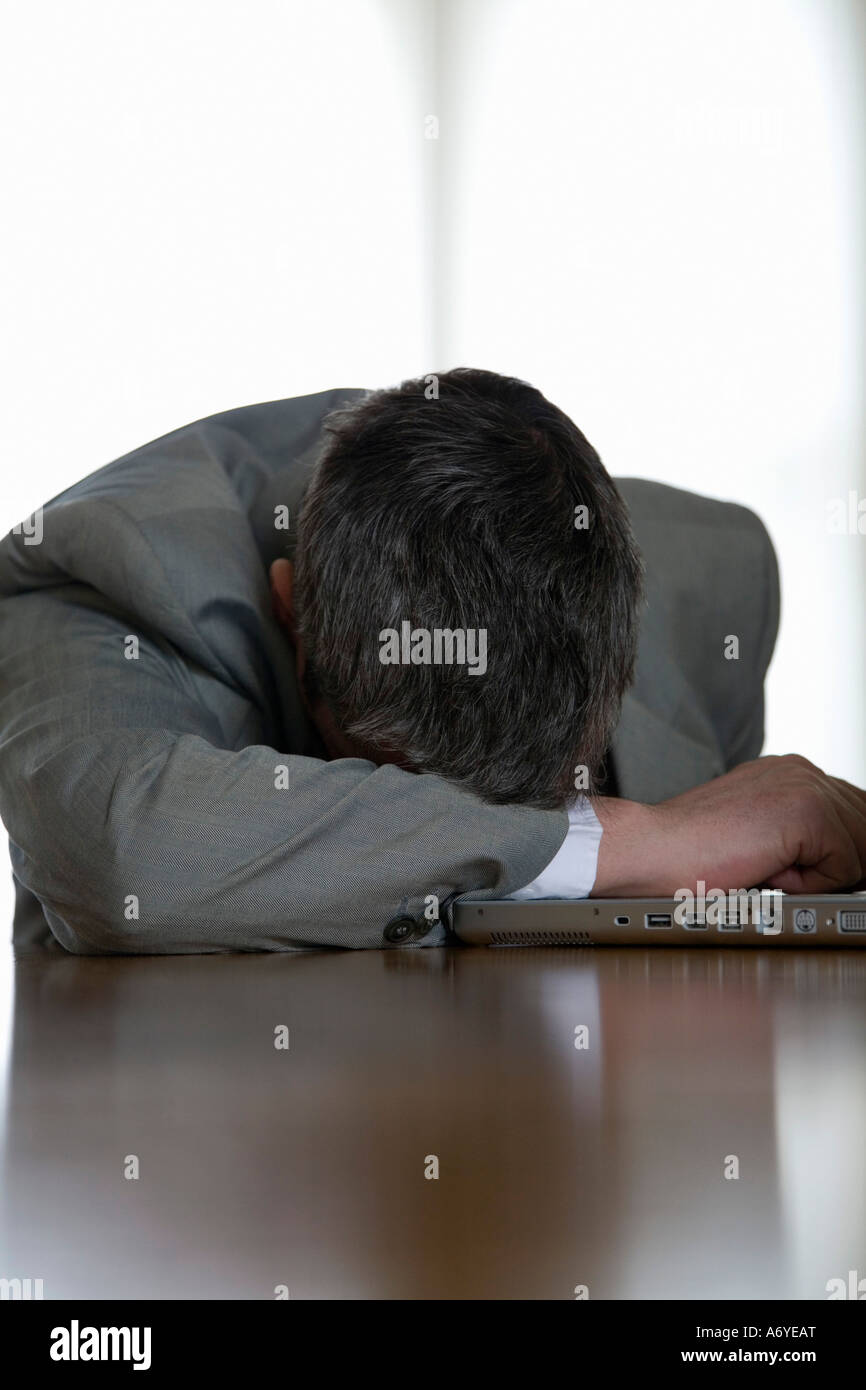 Businessman resting on his laptop at a desk Stock Photo - Alamy