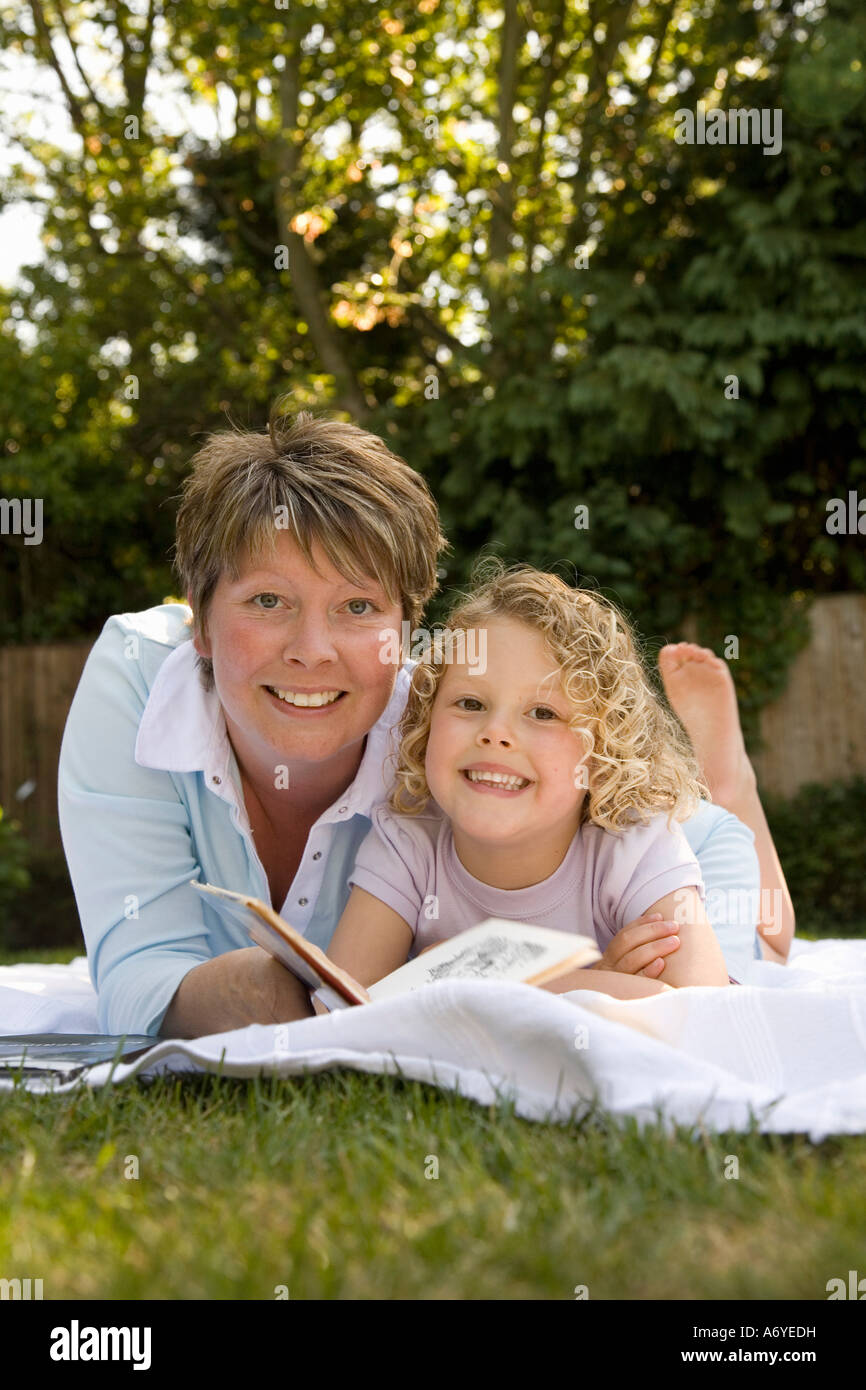 Mother And Daughter Lying Down And Reading A Book Together In A
